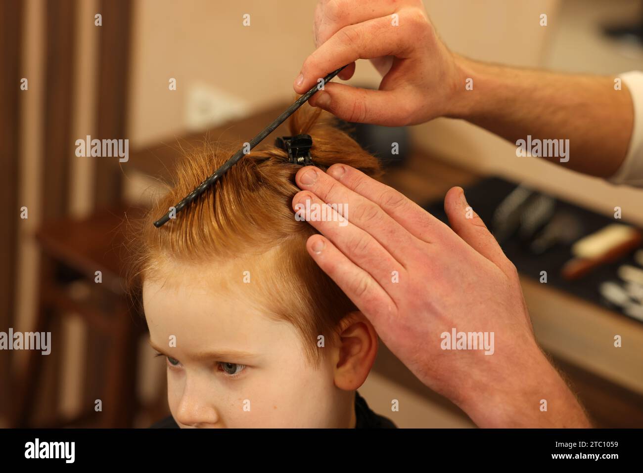 Professional hairdresser combing boy's hair in beauty salon, closeup ...