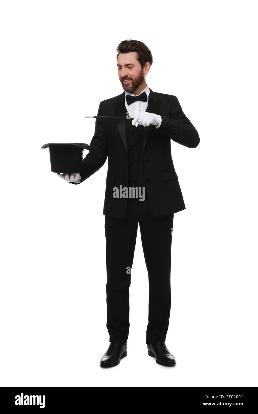 Happy magician showing magic trick with top hat on white background ...