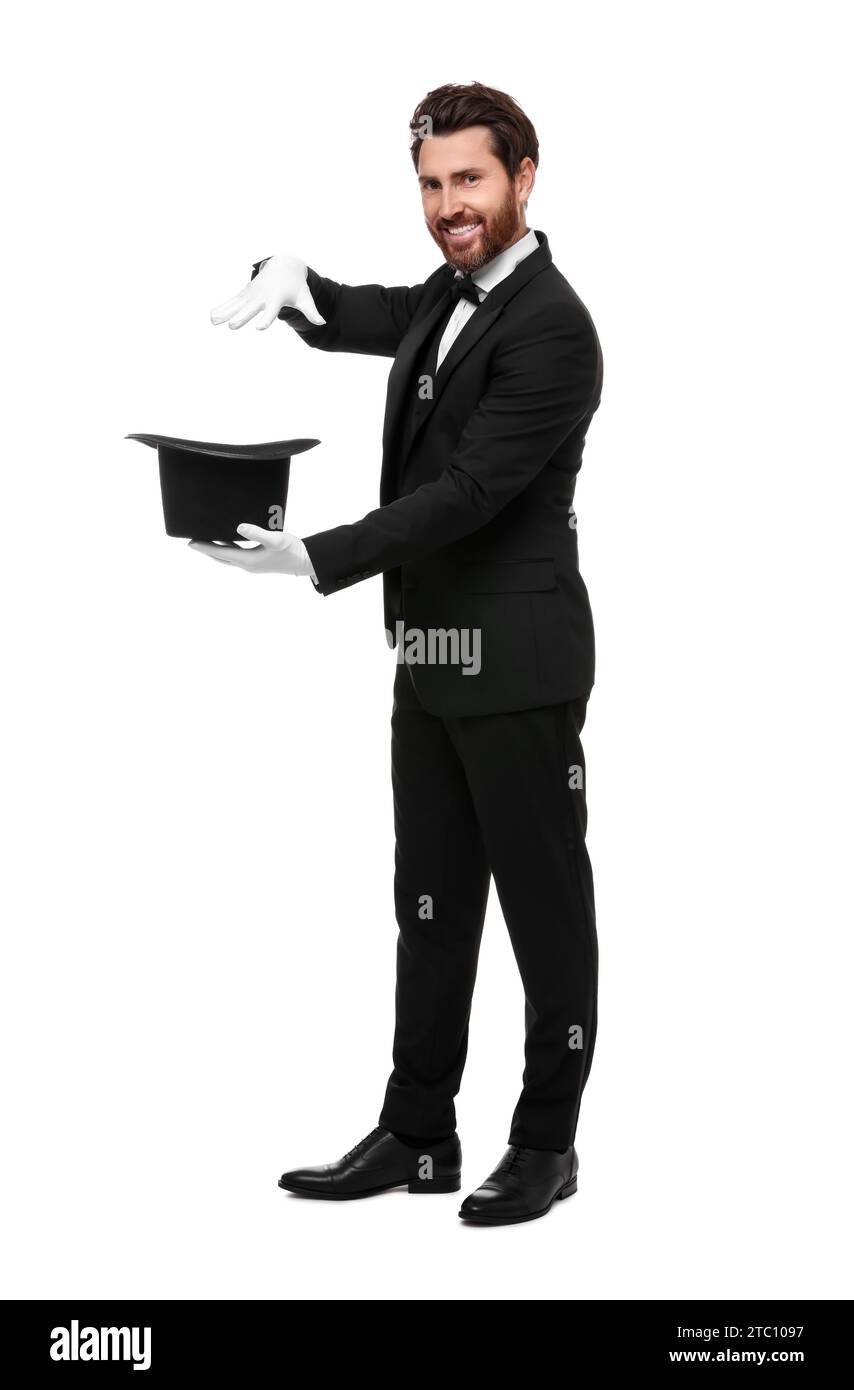 Happy magician showing magic trick with top hat on white background ...