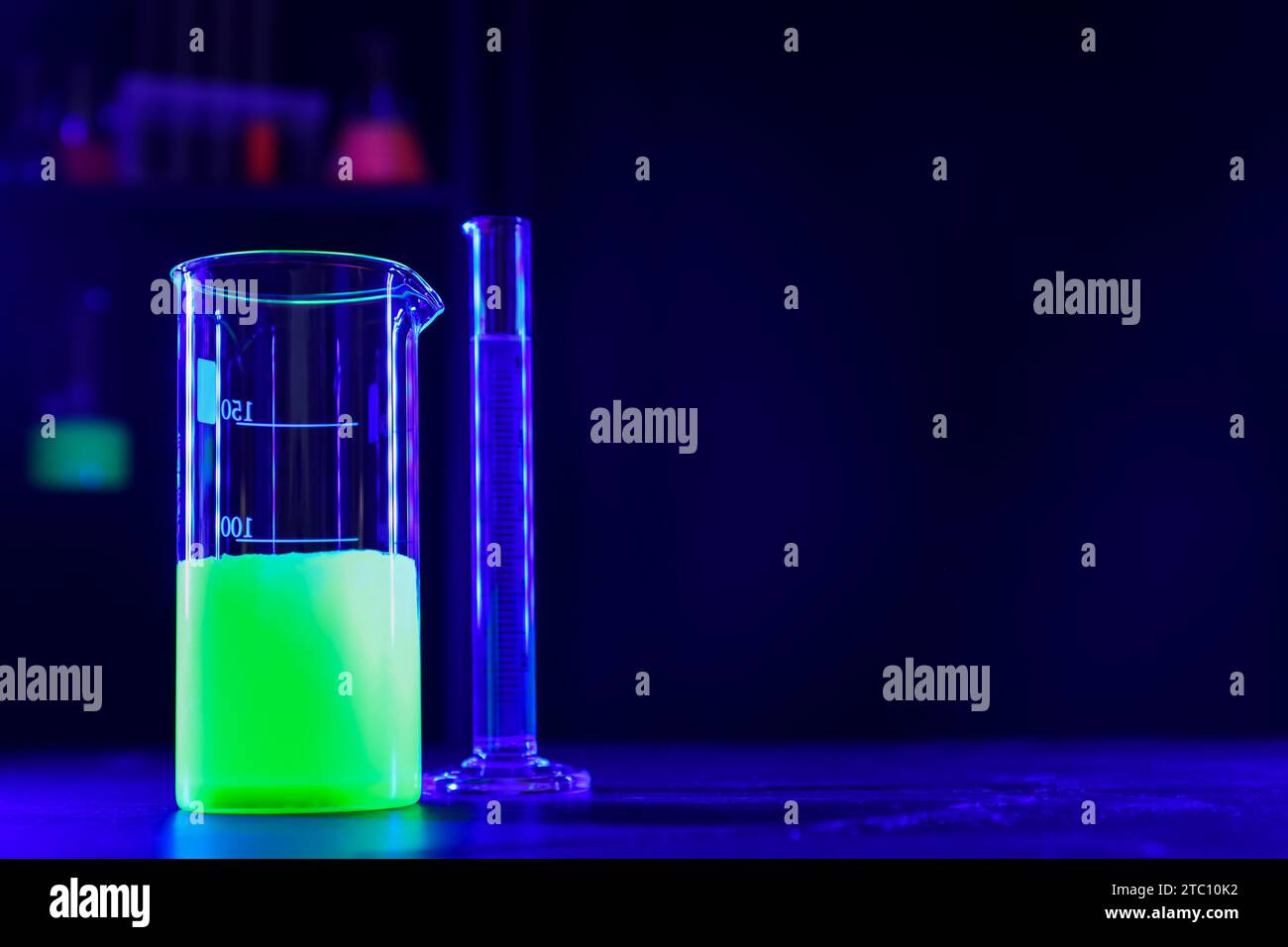Laboratory glassware with luminous liquids on table, space for text ...