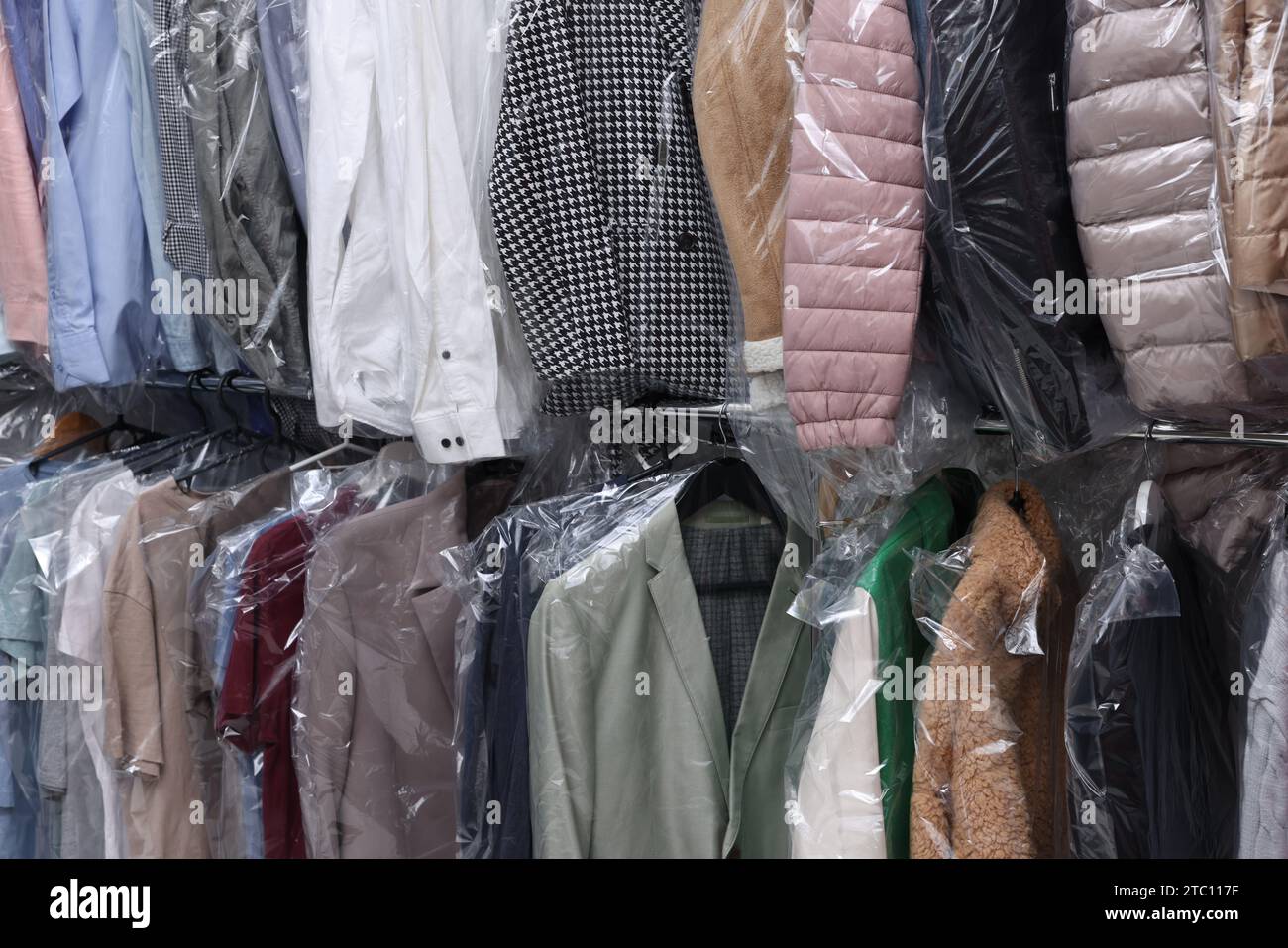 Dry-cleaning service. Hangers with different clothes in plastic bags on ...