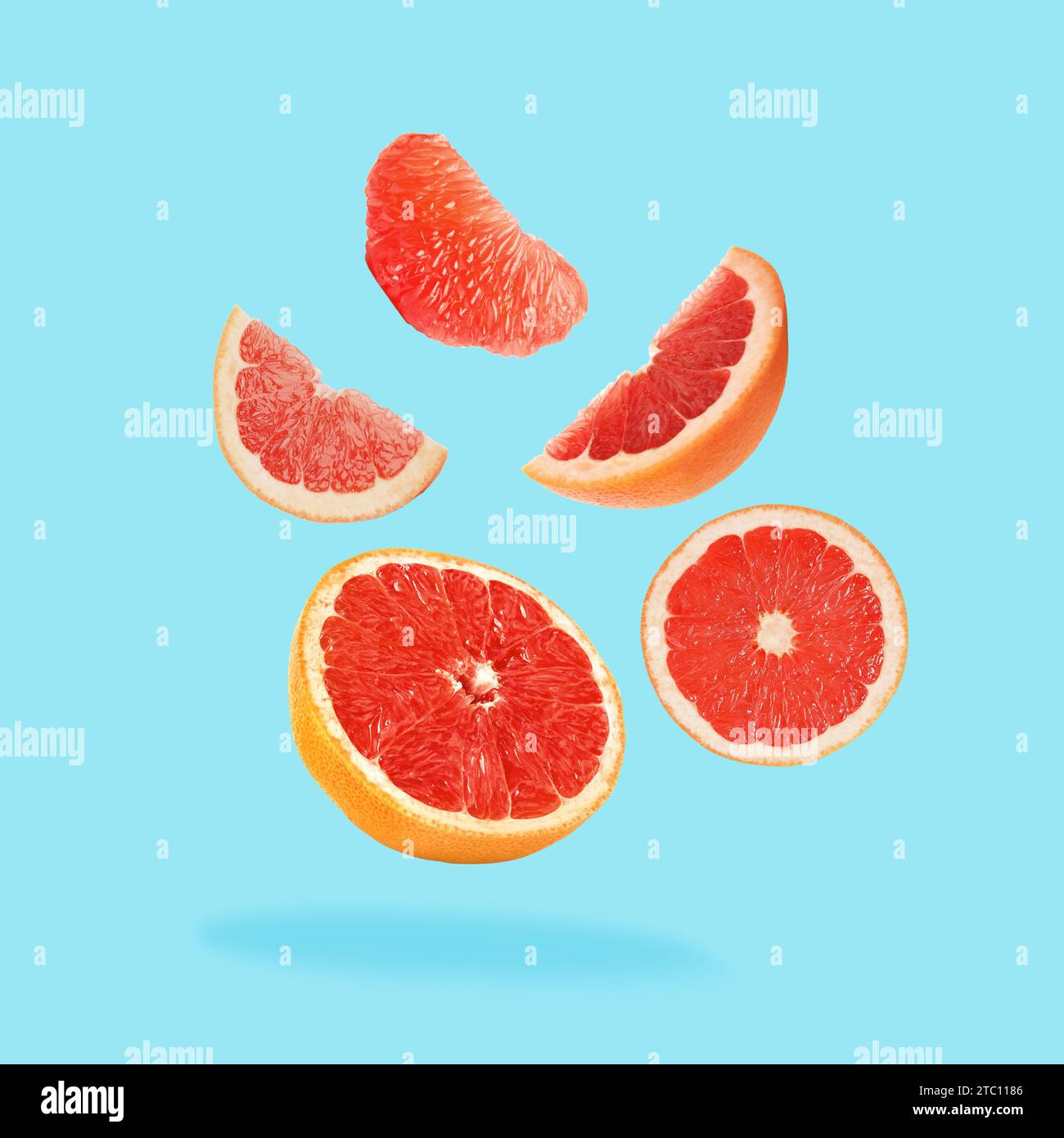 Pieces of grapefruit falling on light blue background Stock Photo - Alamy