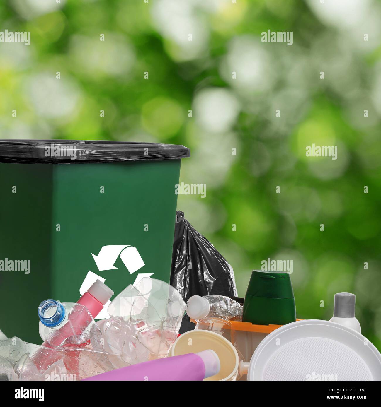 Waste bin surrounded by garbage on blurred background, space for text ...