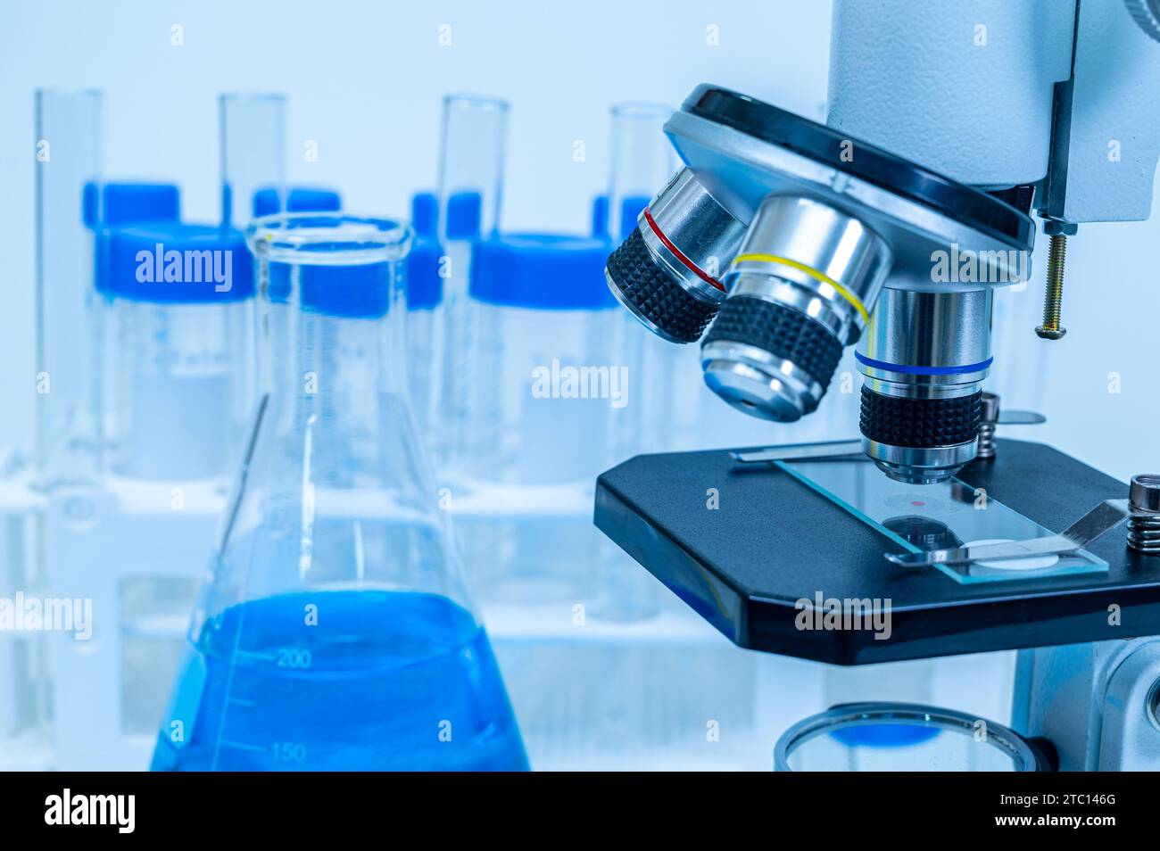 A close-up of a blue liquid erlenmeyer flask and microscope Stock Photo ...