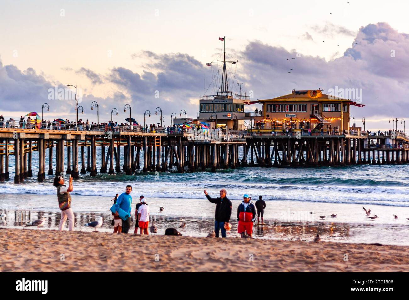 Tourists taking photos on Santa Monica Beach, with Santa Monica Pier in ...