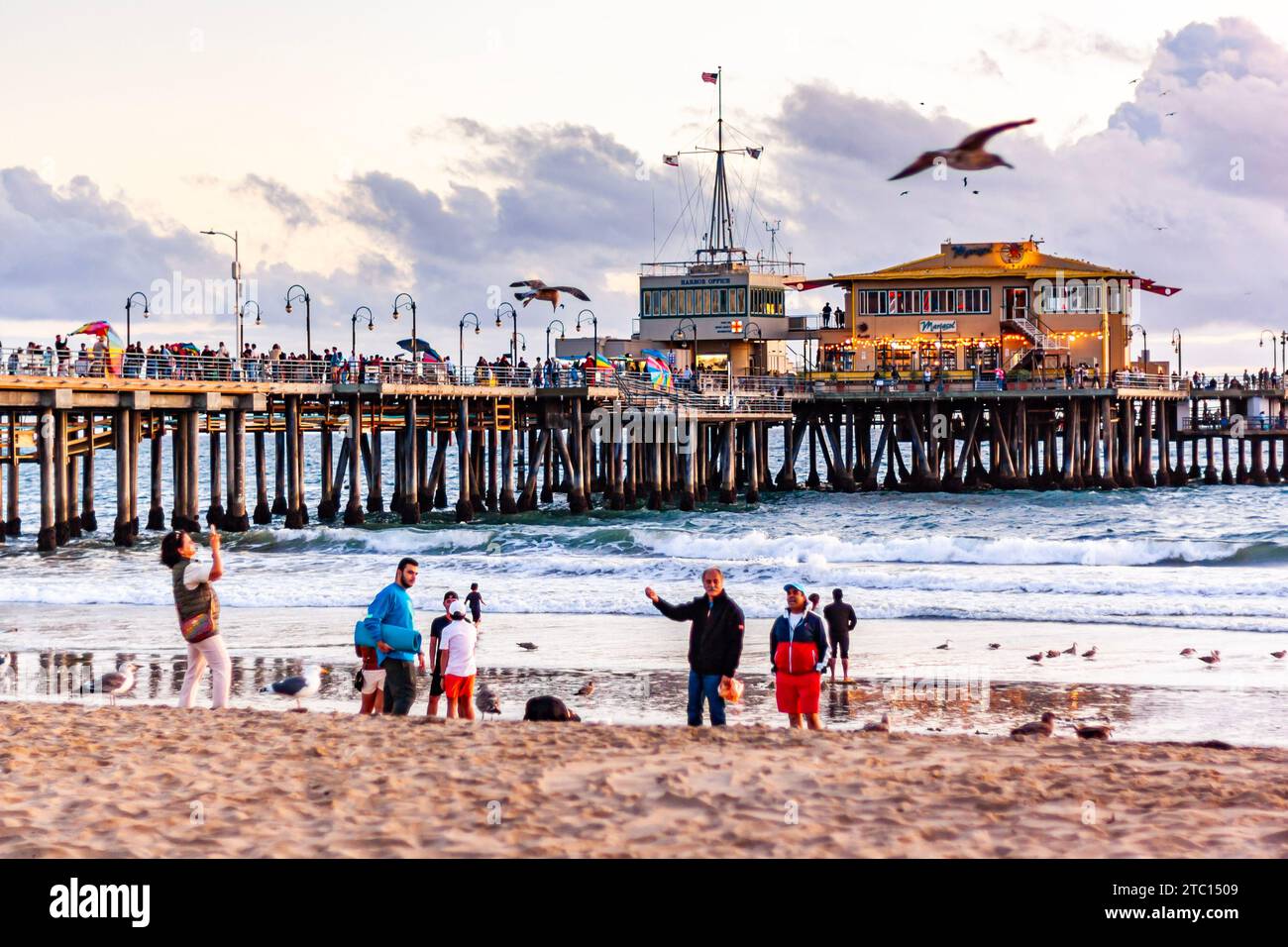 Tourists taking photos on Santa Monica Beach, with Santa Monica Pier in ...