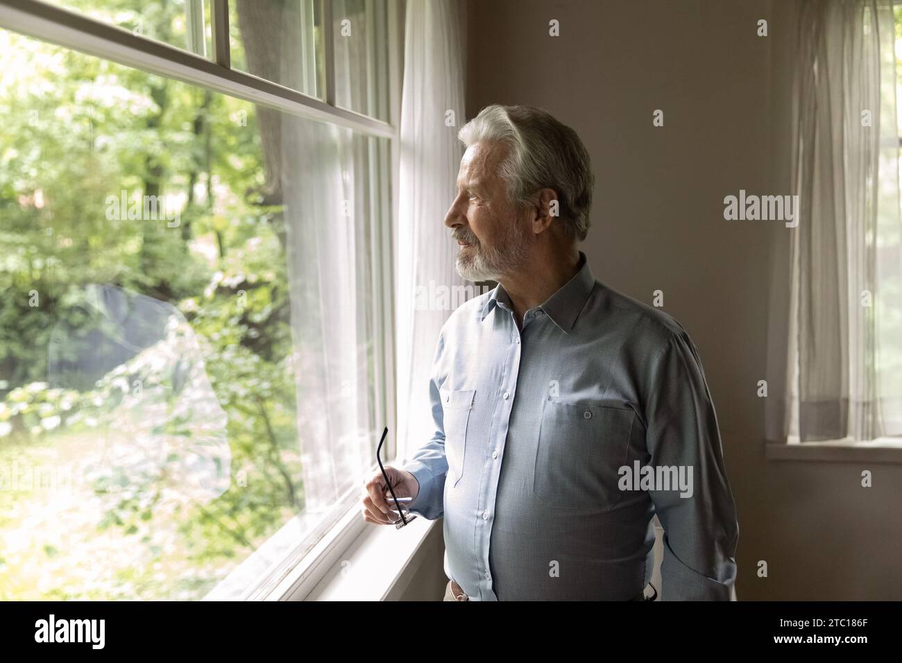 Thoughtful older man standing window hi-res stock photography and ...