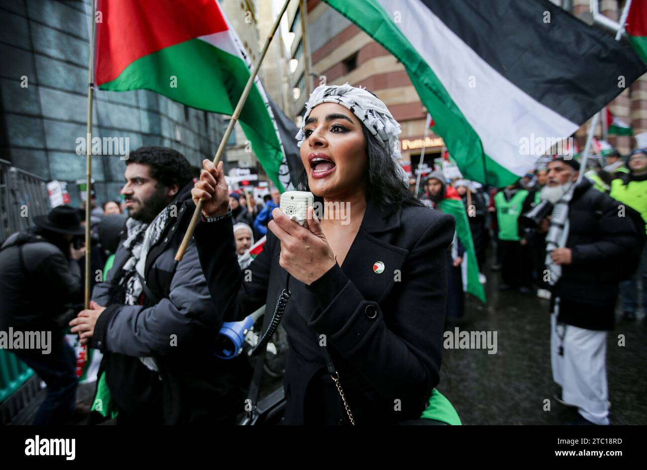 A demonstrator with a keffiyeh wrapped around her head and carrying a ...