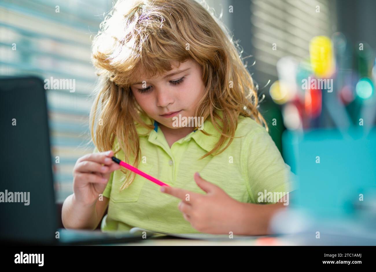 Portrait school kid siting on table doing homework. Child holding ...