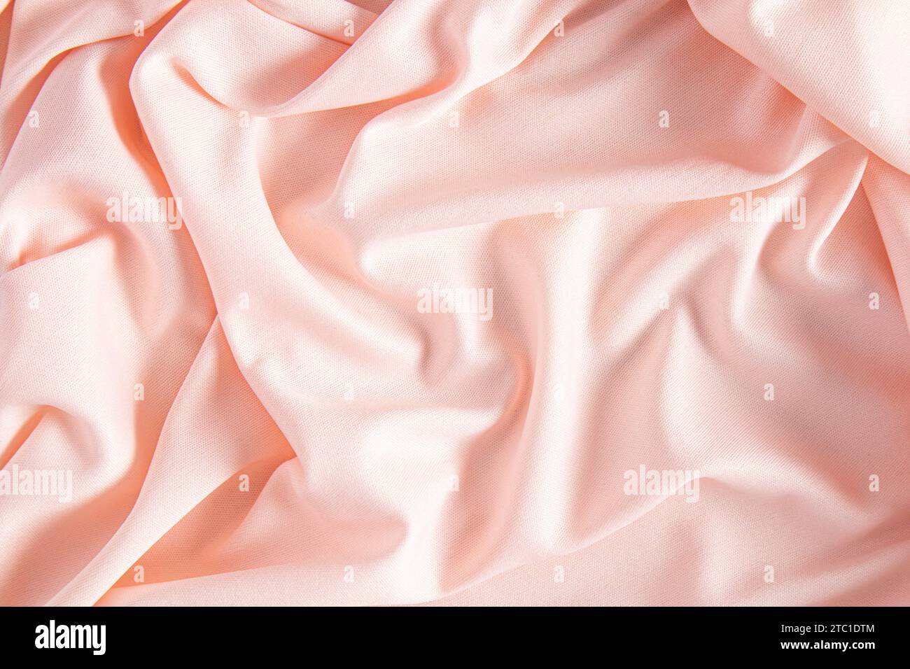 Luxurious satin textiles in peach color. Soft abstract waves of factory ...