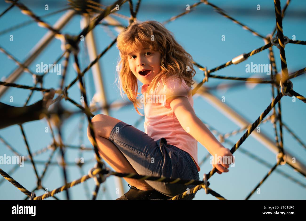 Child climbing the net. Child boy climbed on top of the rope web on ...