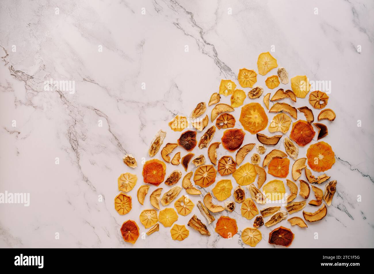 Scattering of fruit chips on half a white marble background with black ...