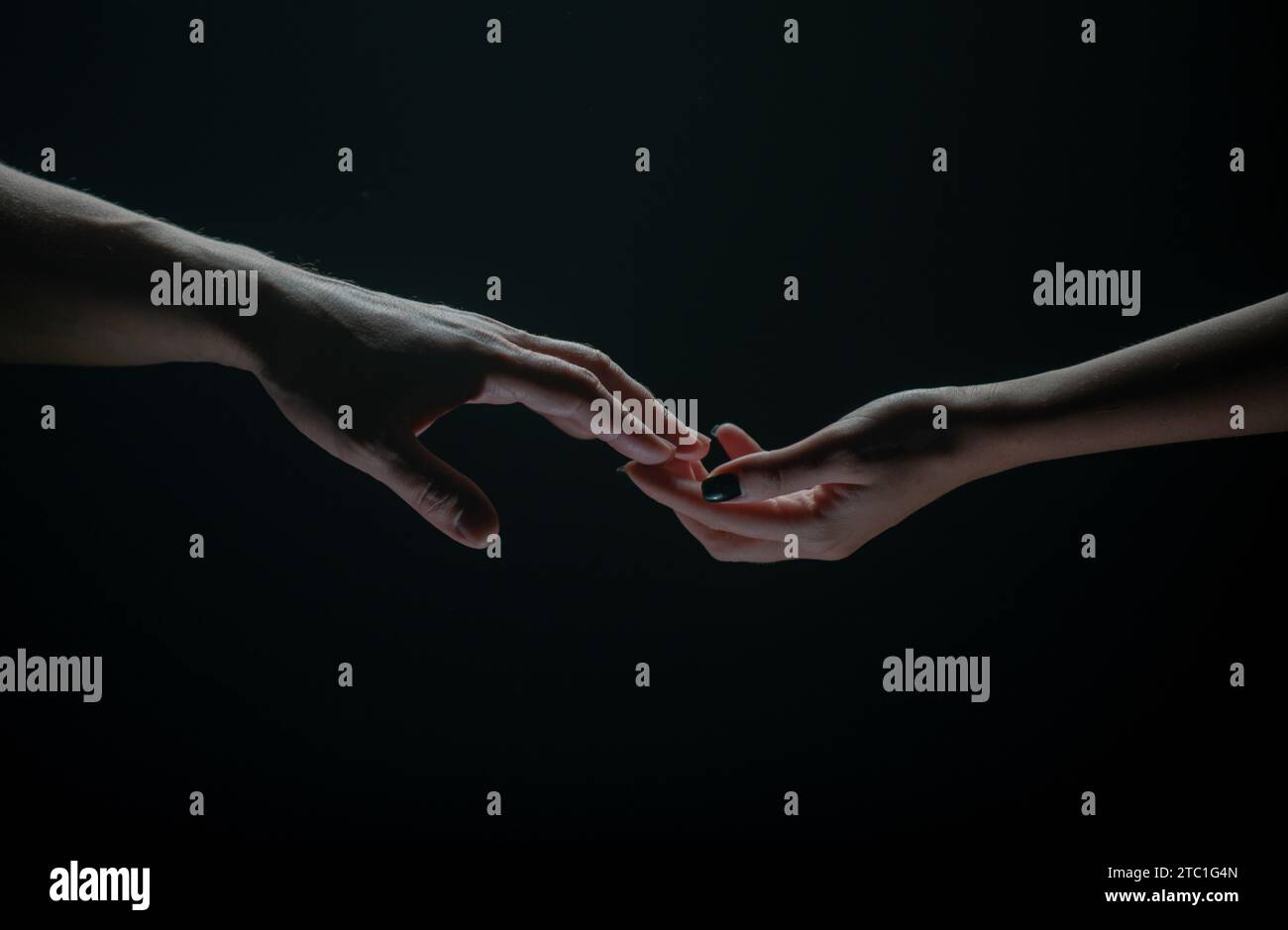 Two hands stretch each other, black background. Couple in love holding ...