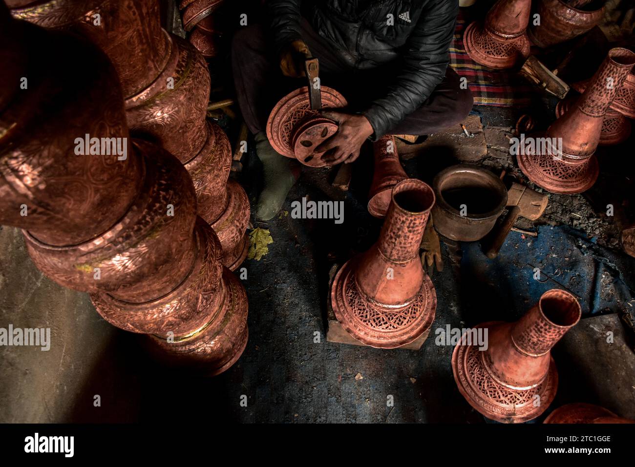 A Kashmiri Coppersmith works on copper utensil at a workshop. Copper ...