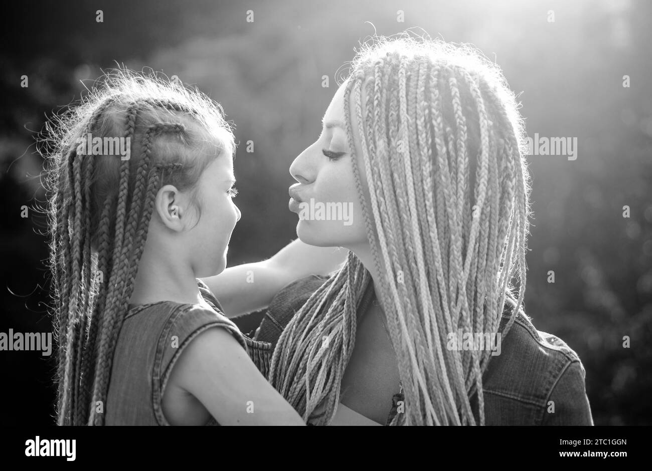 Happy mother and daughter hugging over sun lights background Stock Photo - Alamy
