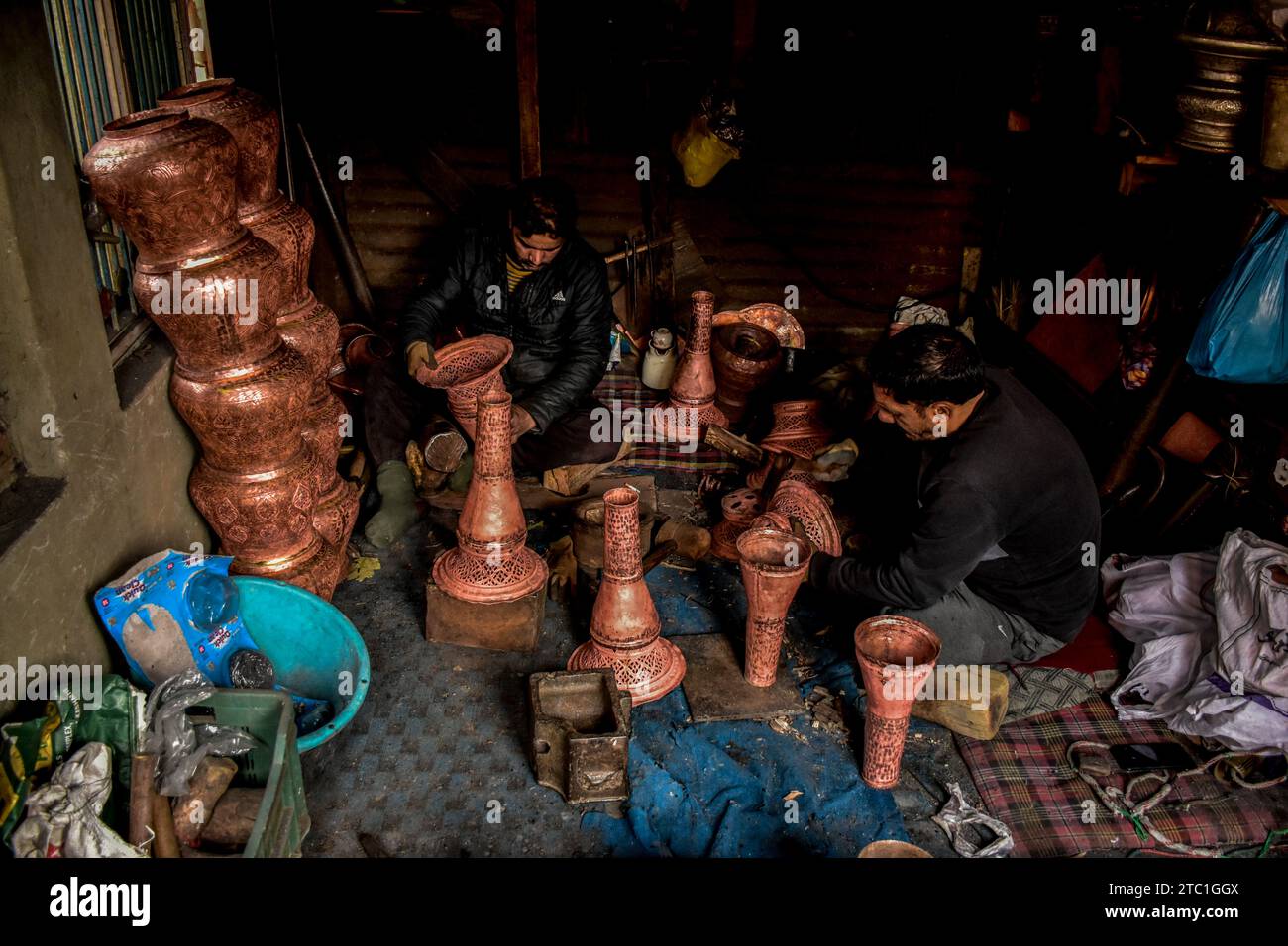 Kashmiri Coppersmiths work on copper utensils at a workshop. Copper ...