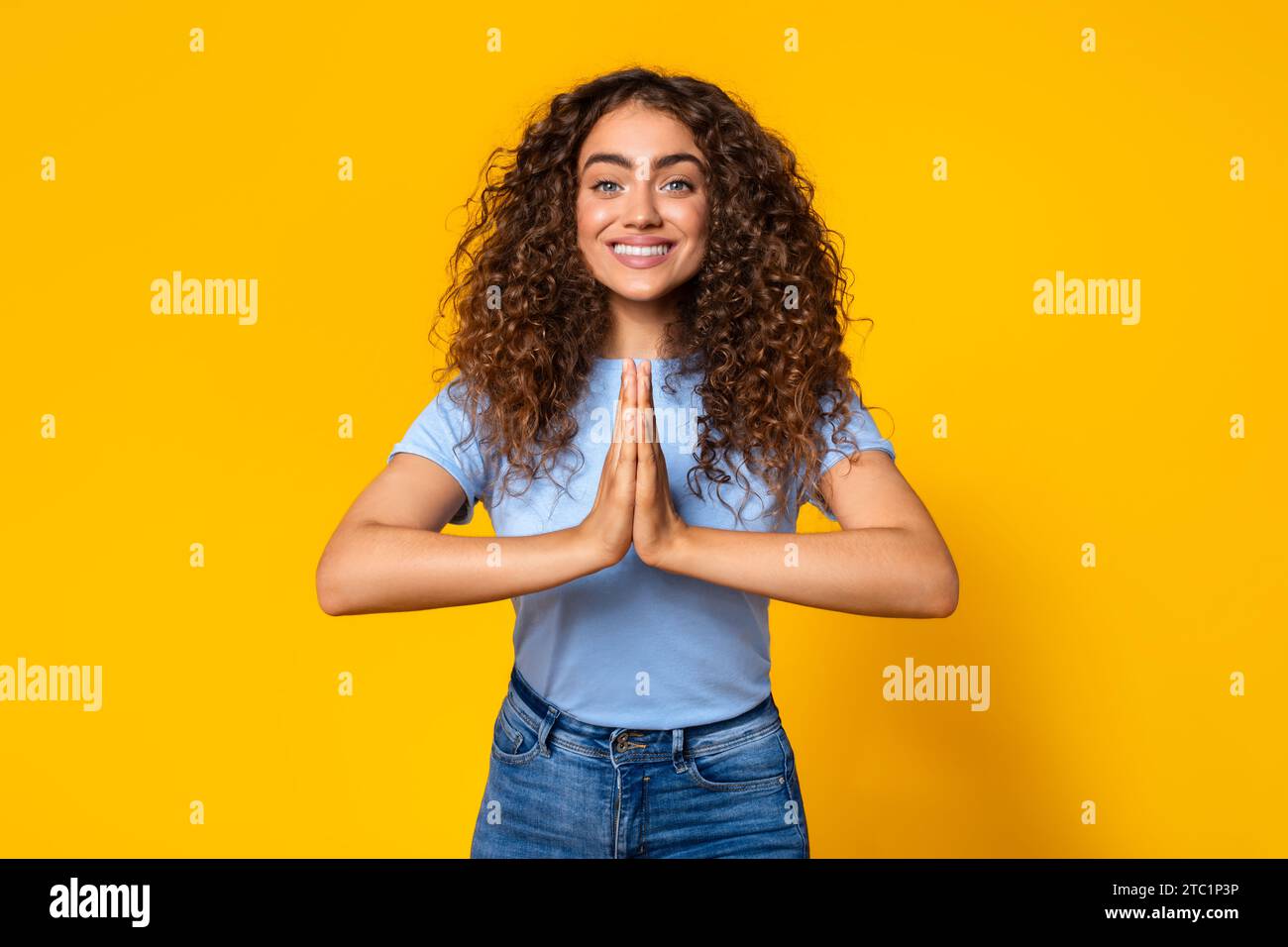 Grateful woman with hands in prayer pose on yellow background Stock ...
