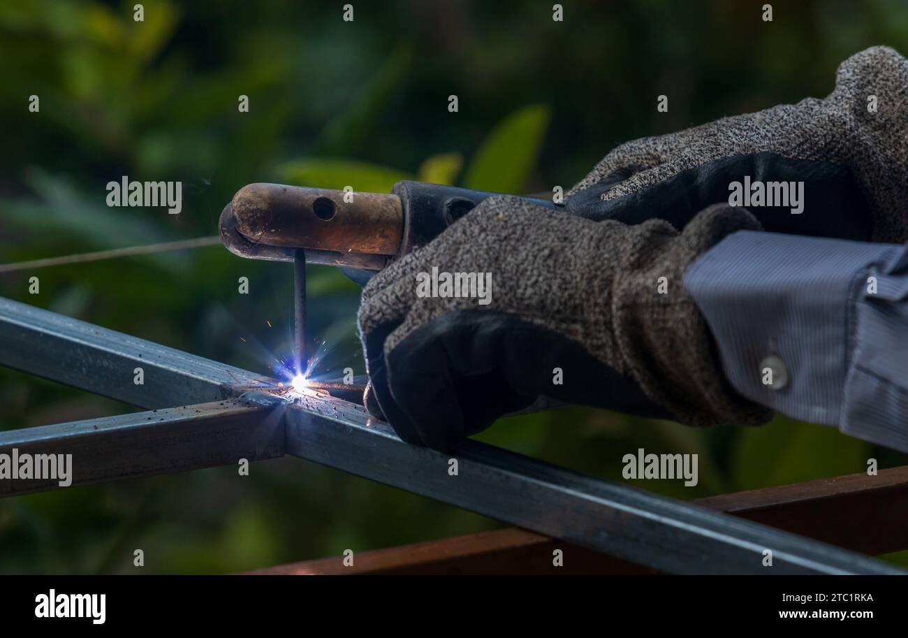 Welder welding galvanized iron frame with proper protection outdoor ...