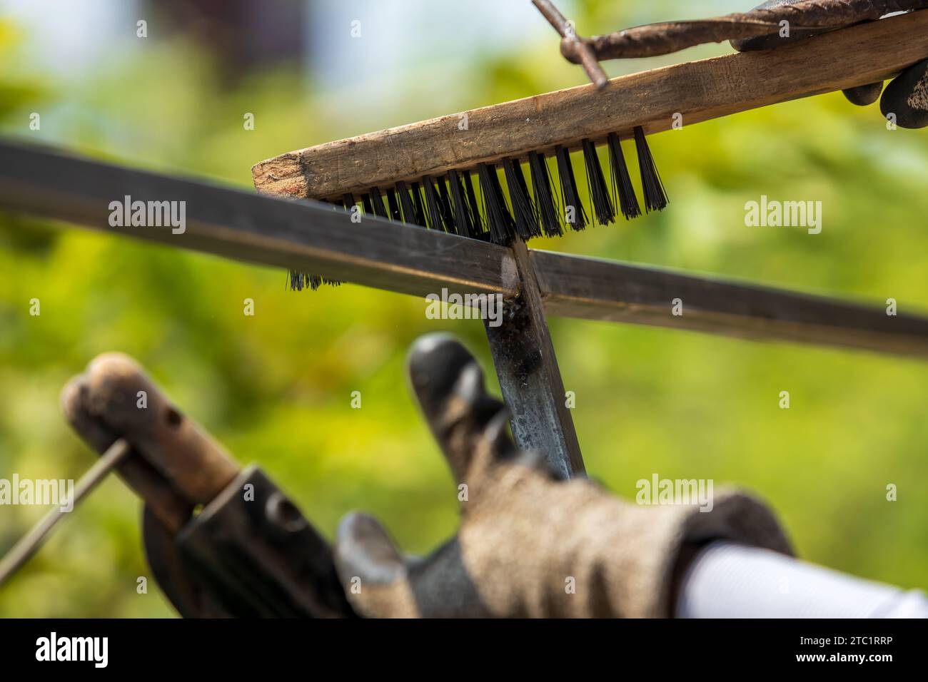 Welder cleans the welding surface using wire brush to remove residue ...