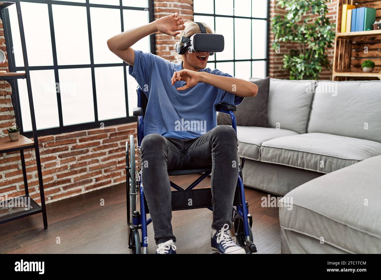 Young blond man playing video game using virtual reality glasses ...