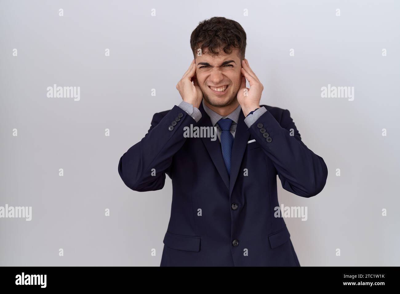 Young hispanic business man wearing suit and tie covering ears with ...