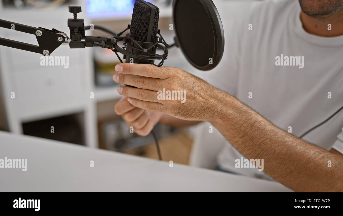 Man's hands at work, reporter speaking passionately on air at informative radio studio amidst ...