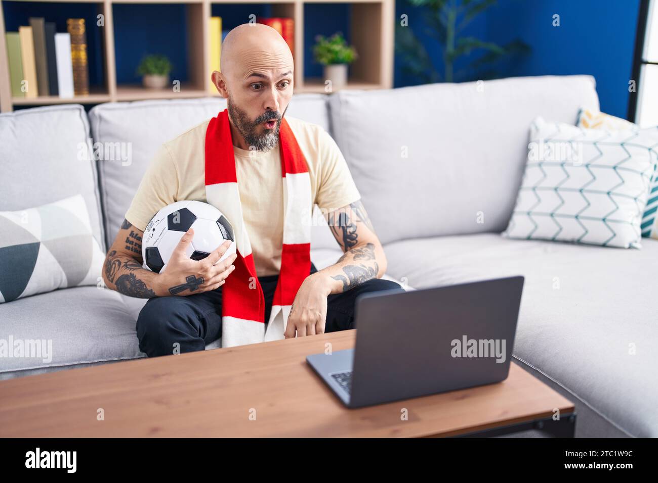 Hispanic man with tattoos watching football match hooligan holding ball ...