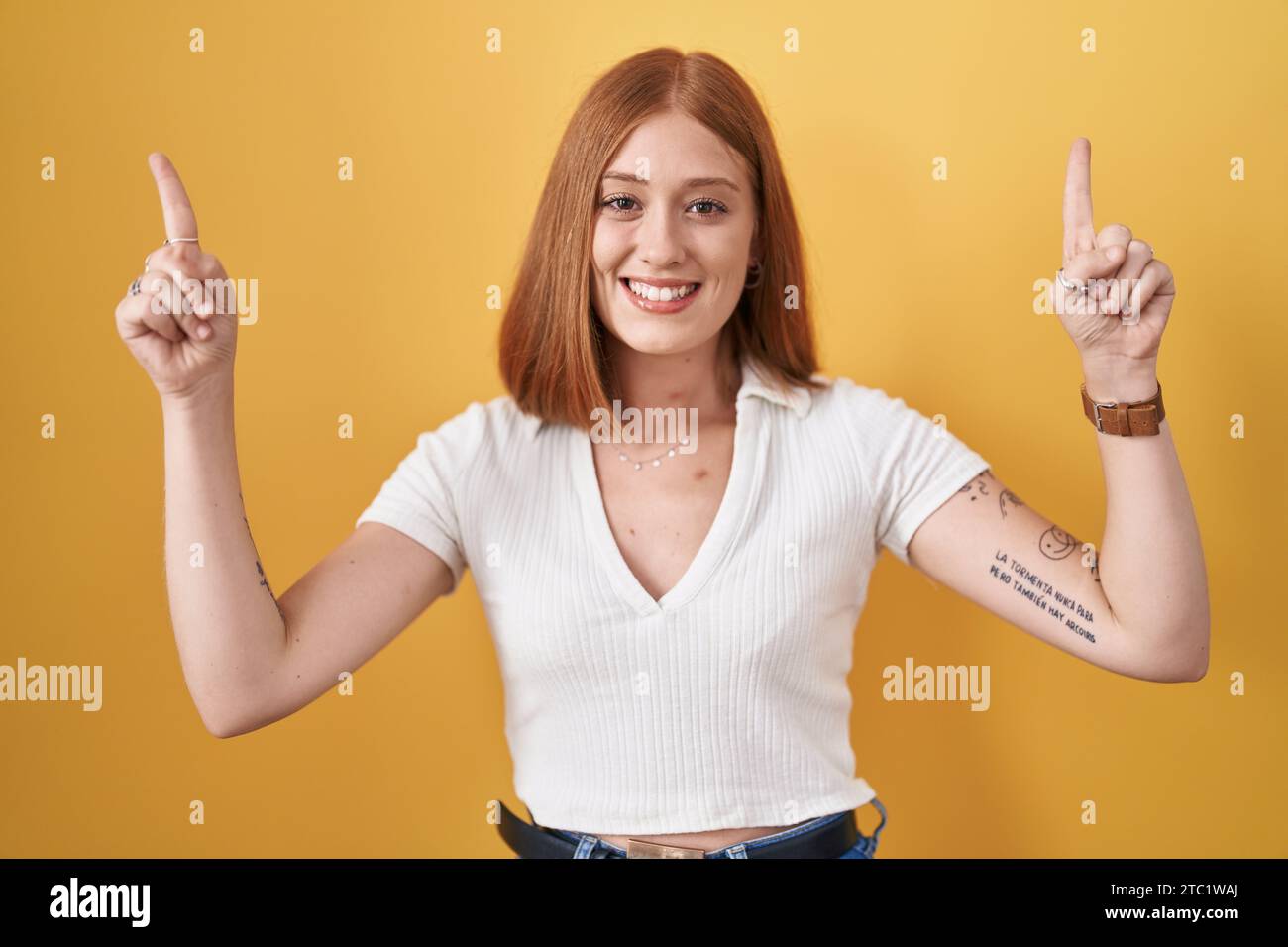 Young redhead woman standing over yellow background smiling amazed and ...