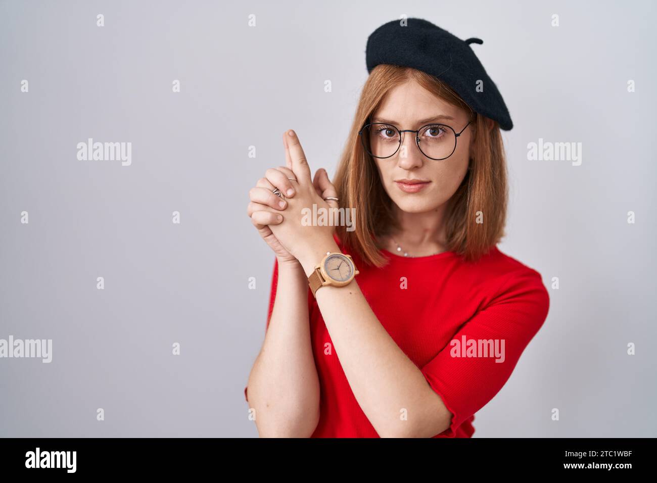 Young redhead woman standing wearing glasses and beret holding symbolic ...