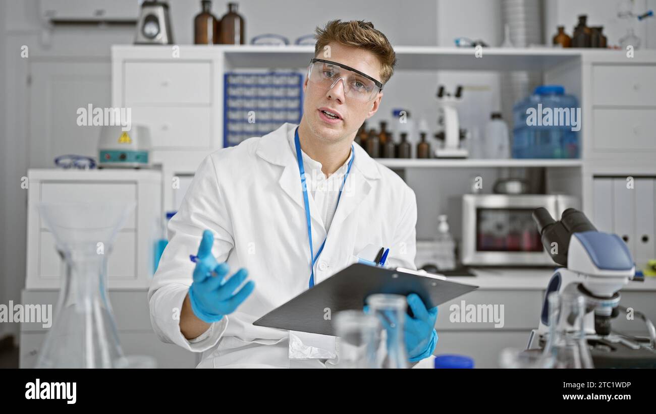 Attractive, smiling young caucasian male scientist, holding clipboard ...