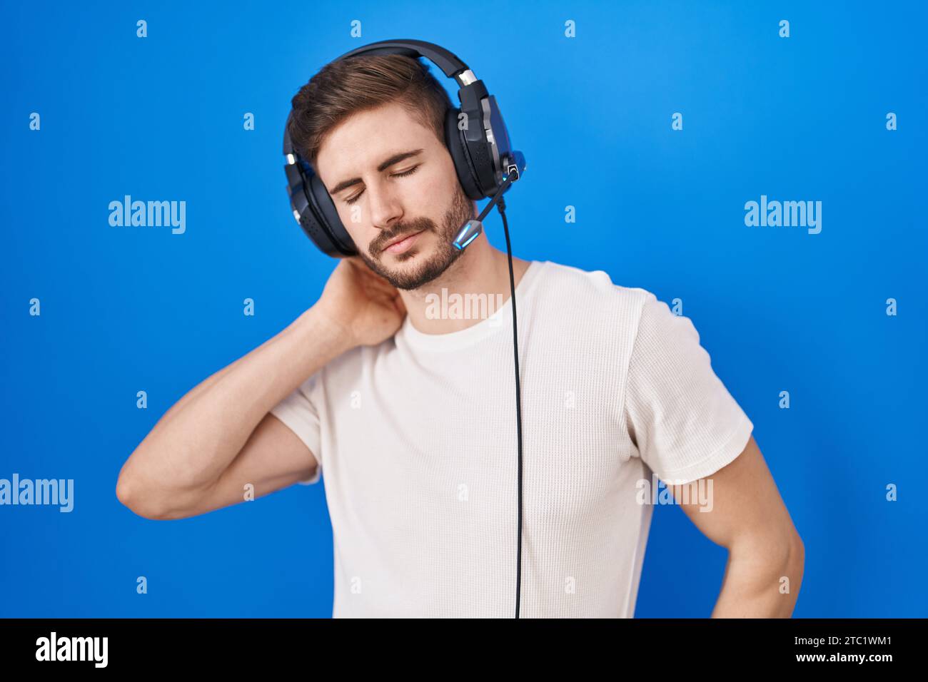 Hispanic man with beard listening to music wearing headphones suffering ...