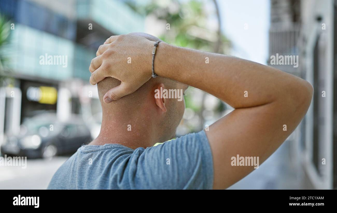 Young hispanic man standing backwards touching head at street Stock ...