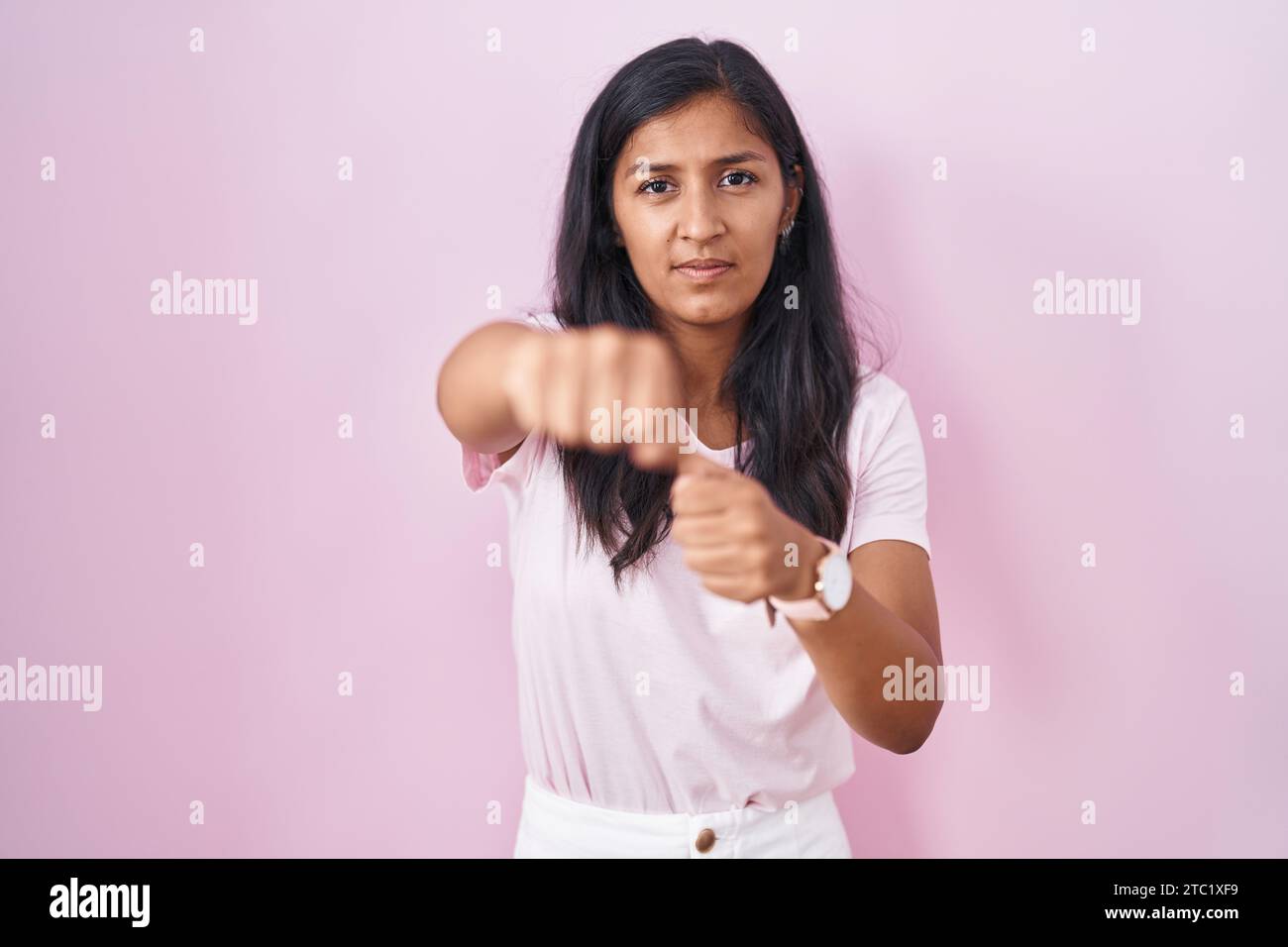 Young Hispanic Woman Standing Over Pink Background Punching Fist To 1691