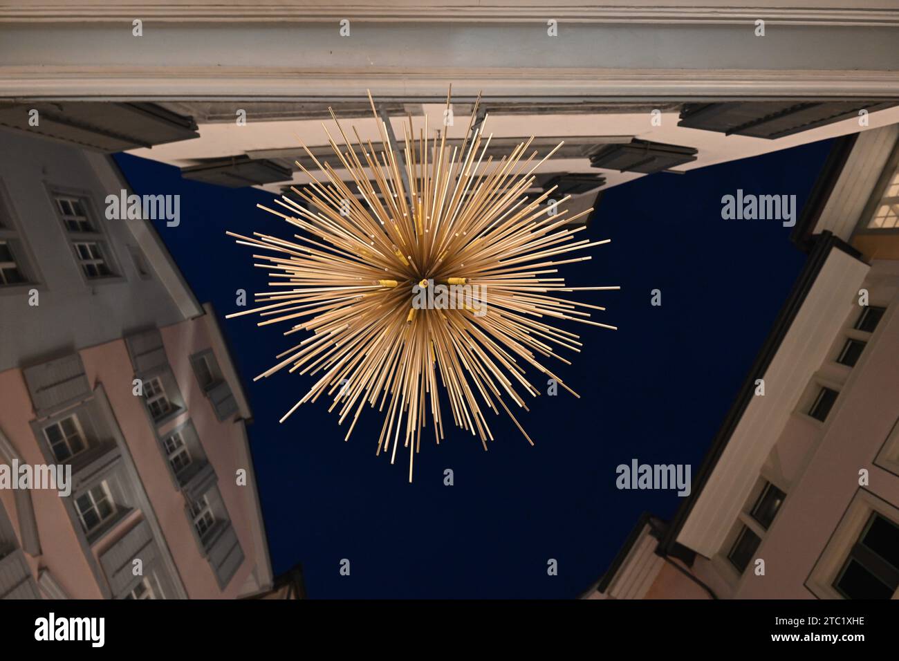 A stunning illuminated sunburst hanging from a building against a ...