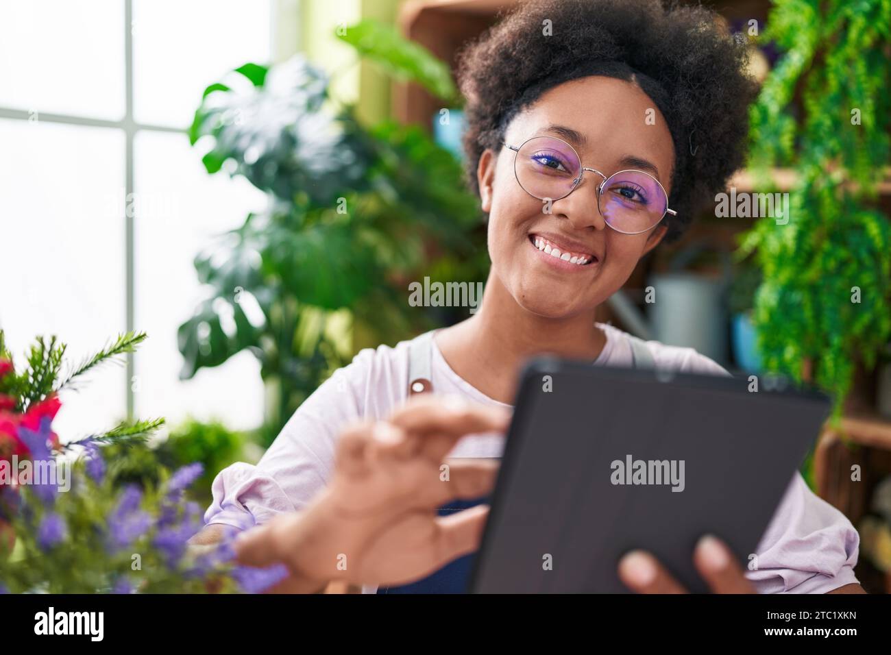 African american woman florist smiling confident using touchpad at ...