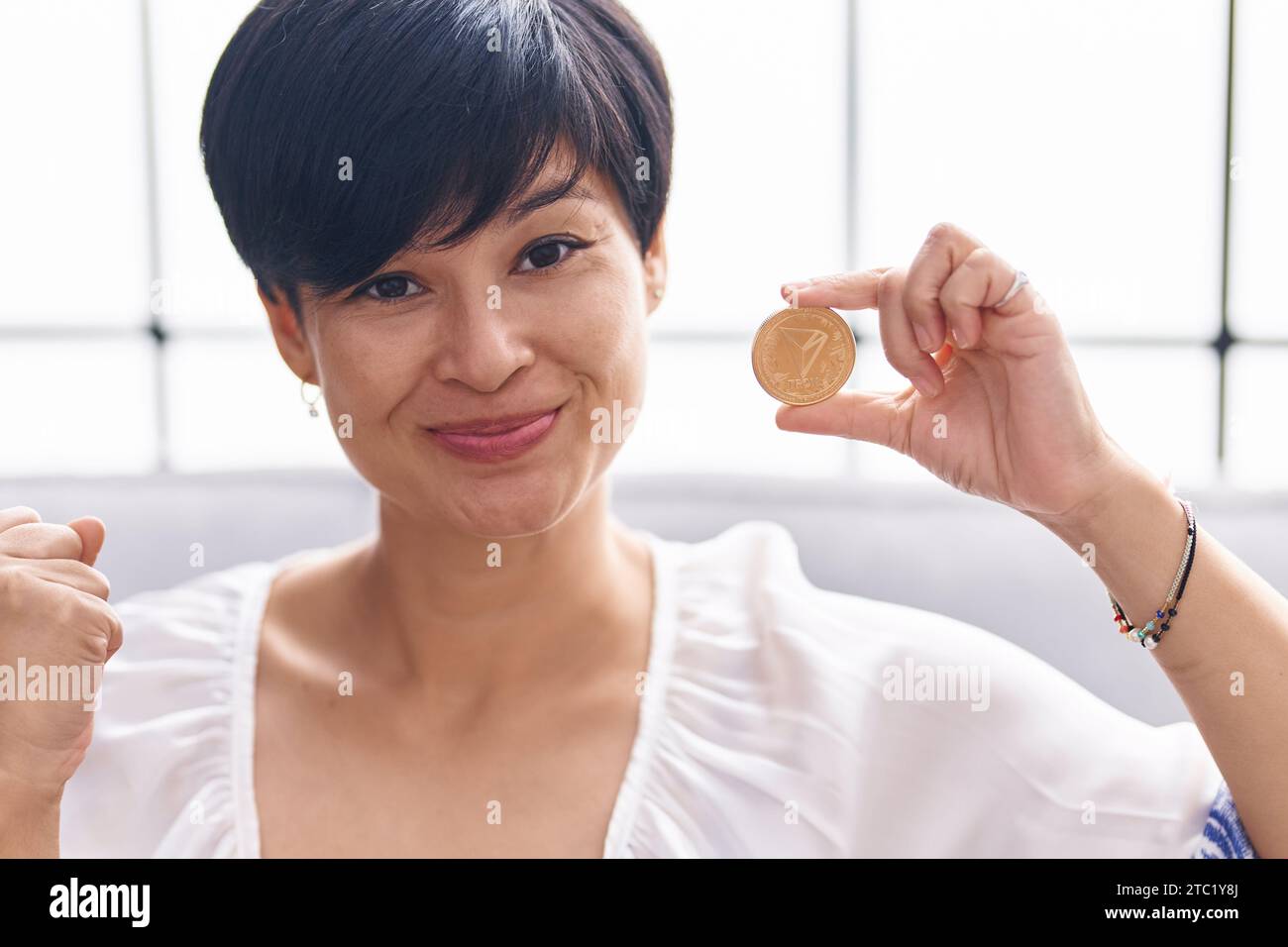 Young asian woman with short hair holding tron cryptocurrency coin ...