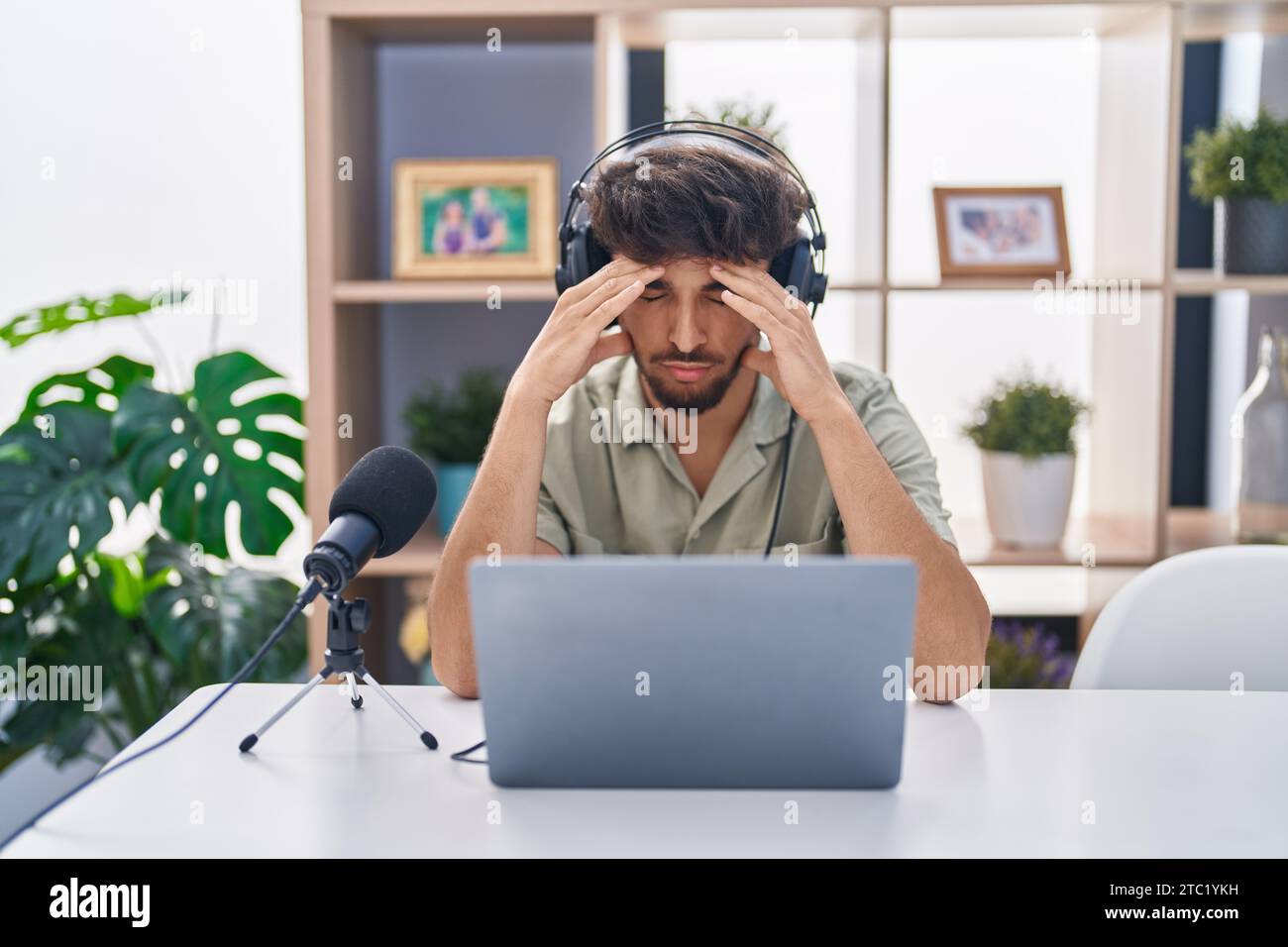 Arab man with beard working at the radio suffering from headache ...