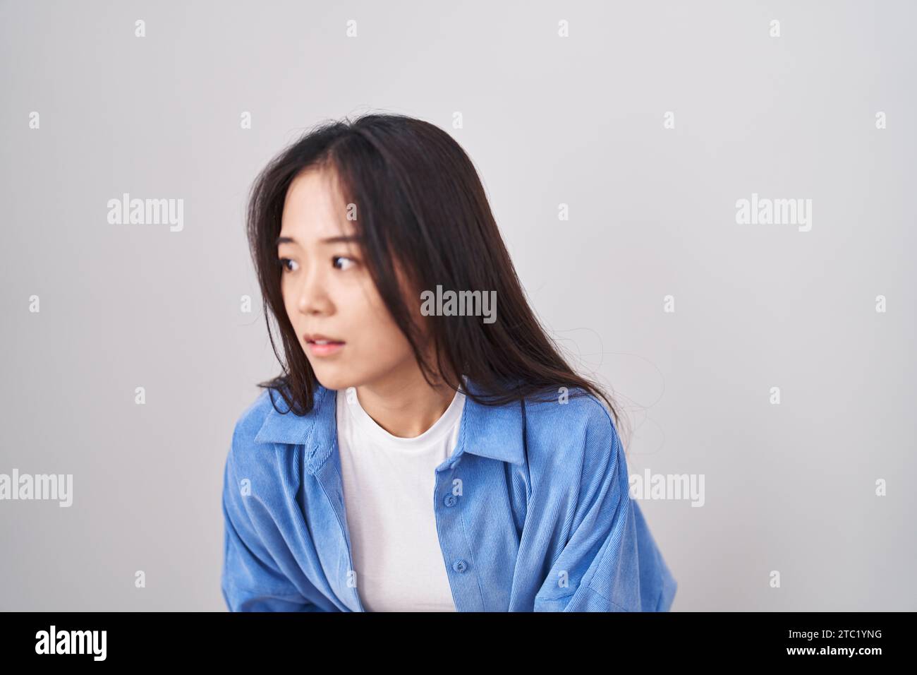 Young chinese woman standing over white background with hand on stomach ...