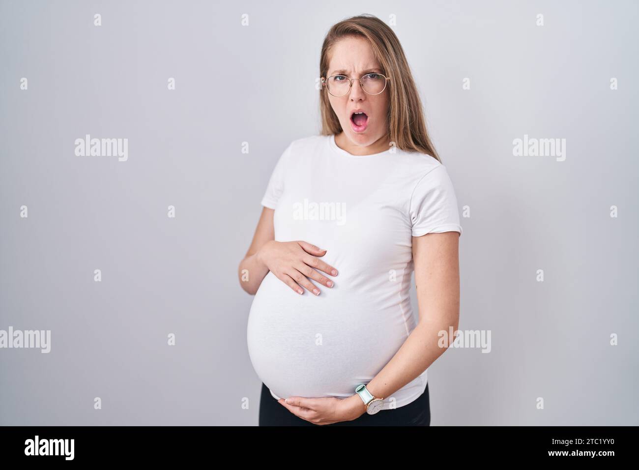 Young pregnant woman expecting a baby, touching pregnant belly in shock ...