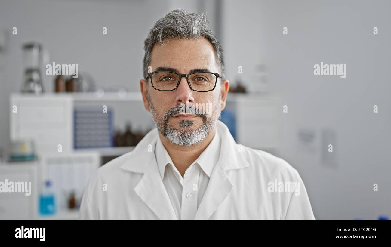 Handsome, grey-haired young hispanic male scientist seriously focused on medical experiment ...