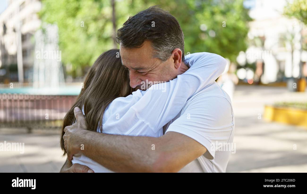 Confident father sharing sunny, joyful hug with smiling daughter at ...