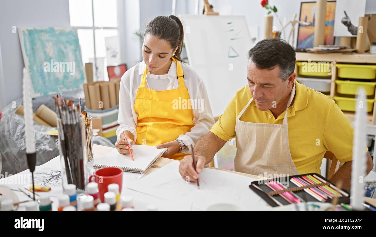 Man and woman artists, deep in concentration, sitting together in art ...