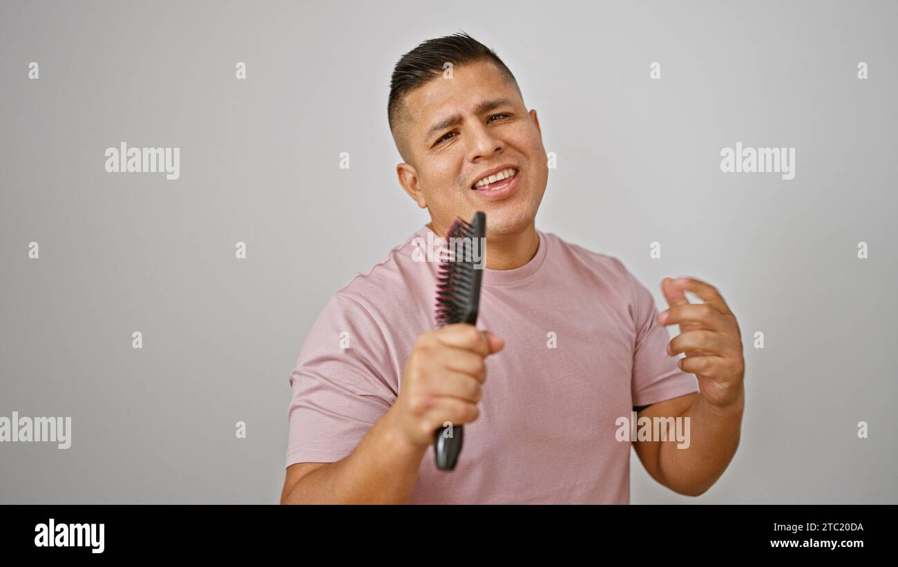 Handsome young latin man joyfully singing his heart out, using a brush ...