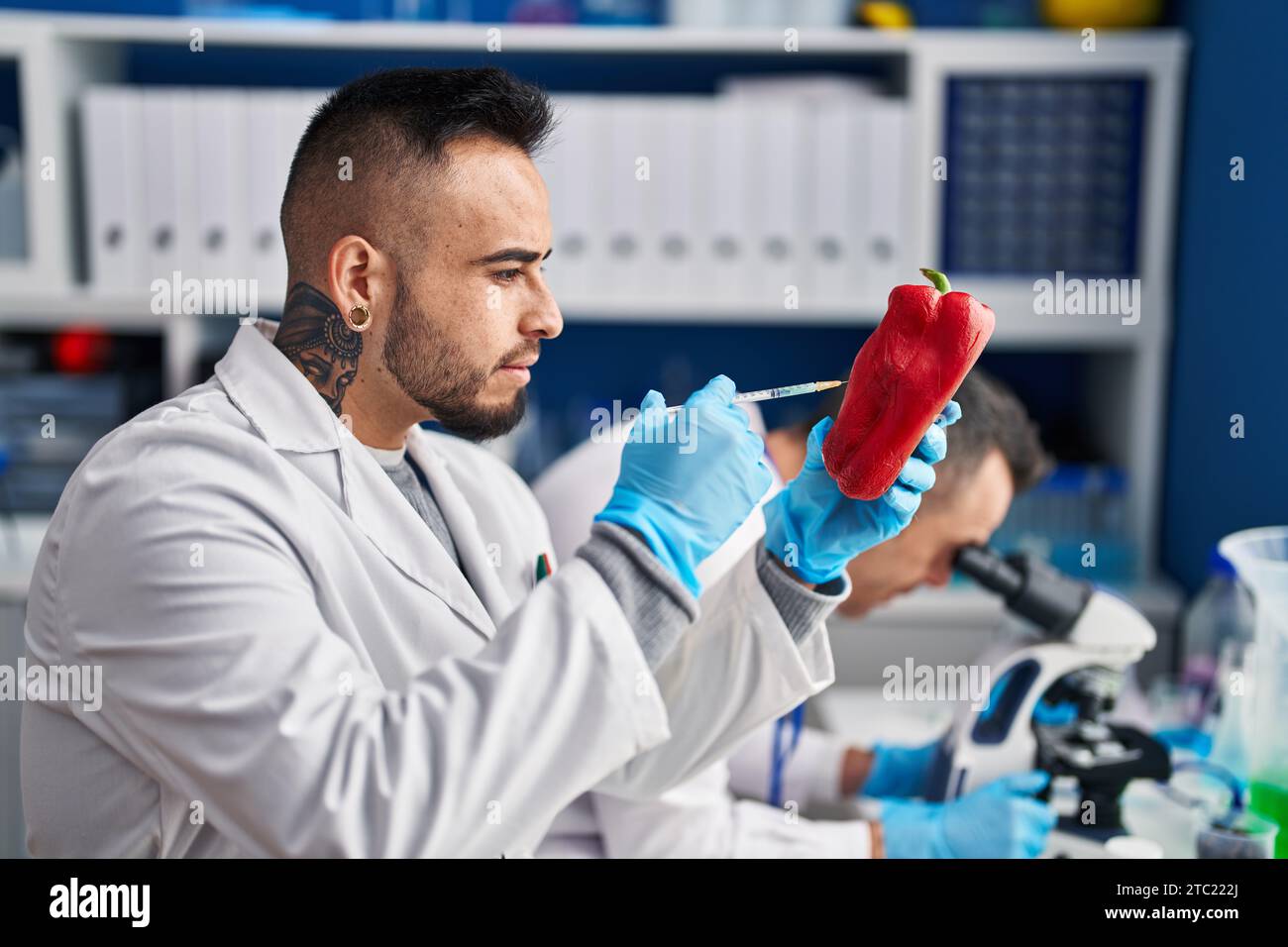 Two men scientist injecting liquid on red pepper using microscope at ...