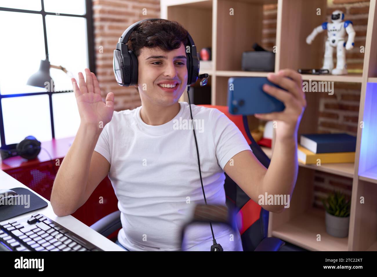 Young non binary man playing video games with smartphone looking ...