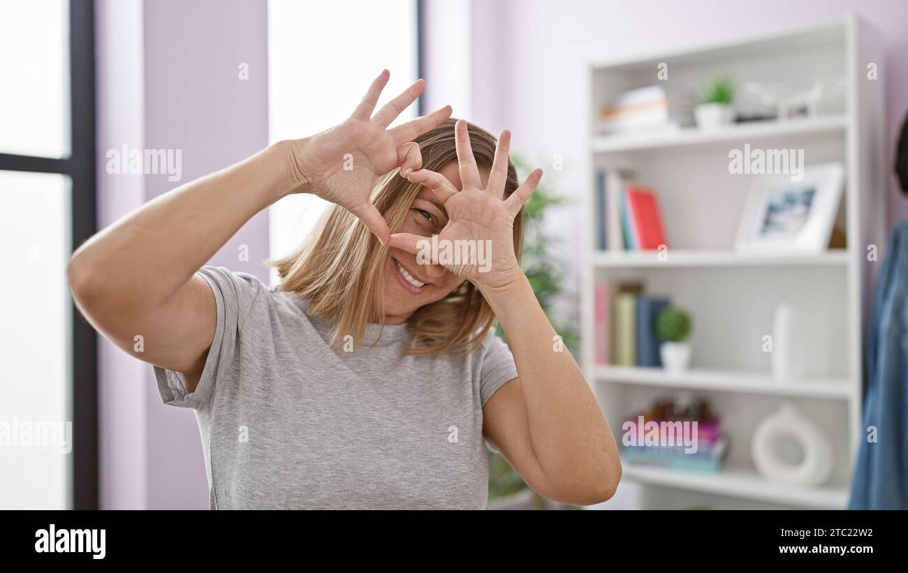Happy young blonde woman radiating joy, confidently creating heart ...