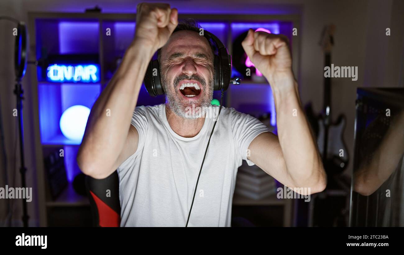 Cheerful middle age man with grey hair ecstatically celebrates his win ...