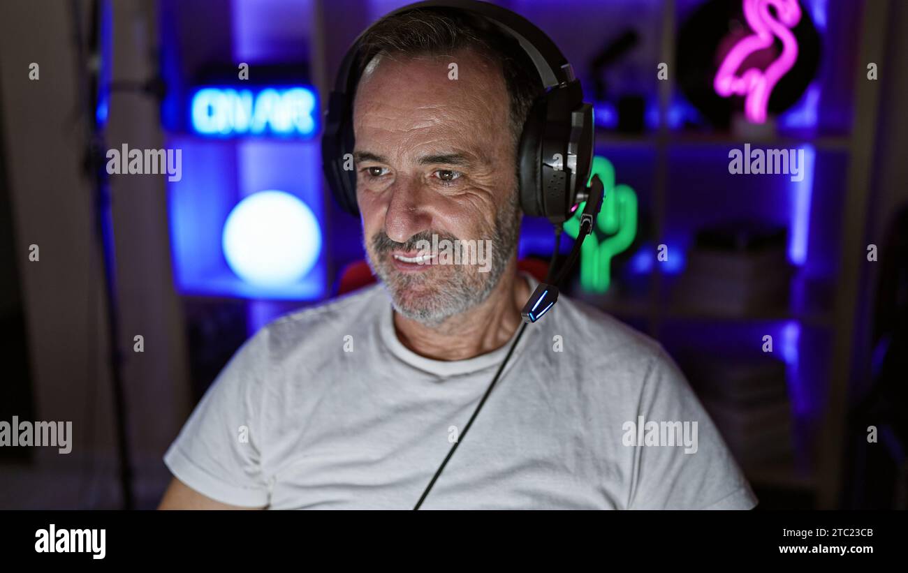 Confident middle-aged gamer with grey hair joyfully streaming his ...