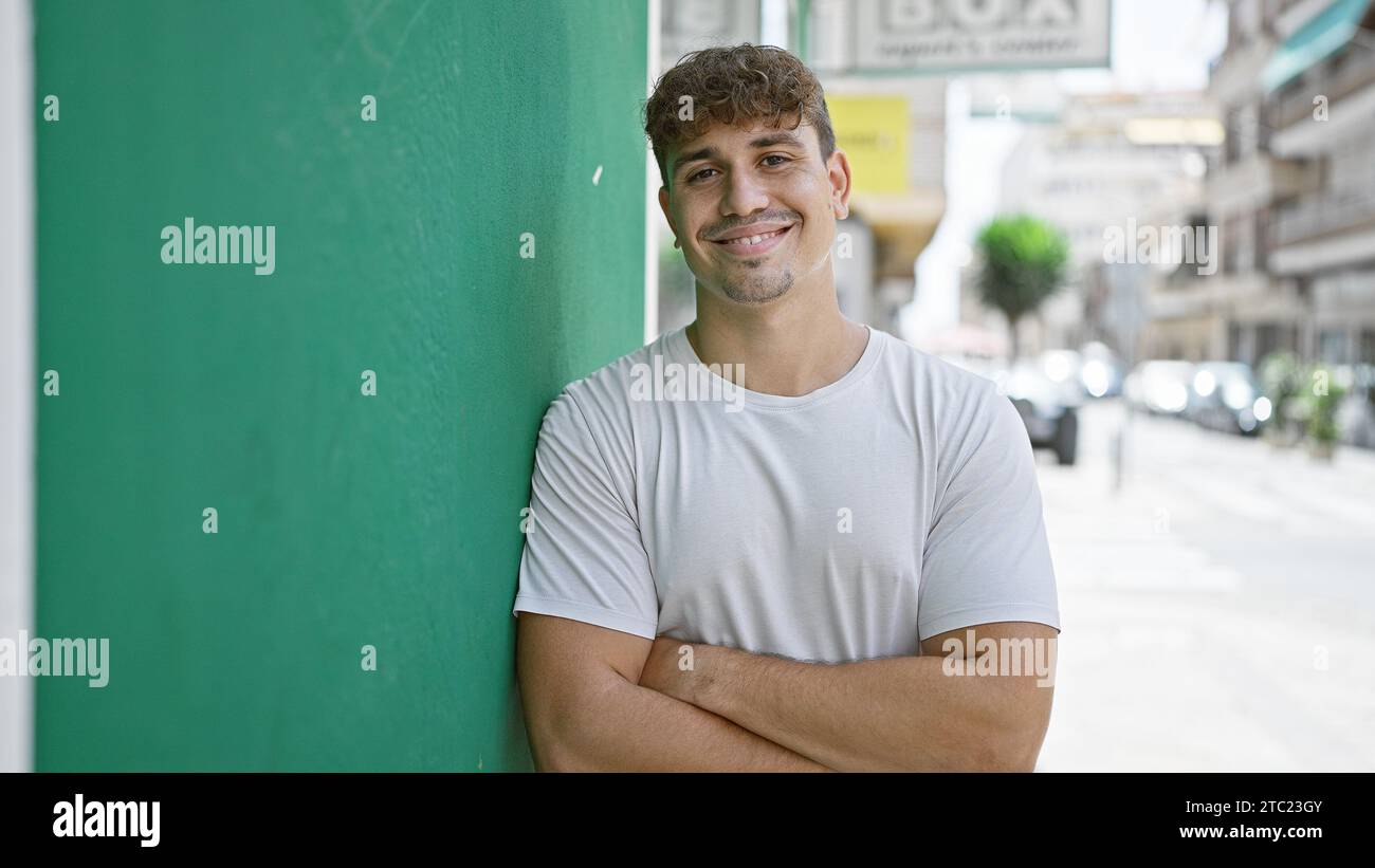 Joyful young hispanic man radiating confidence while standing on a ...