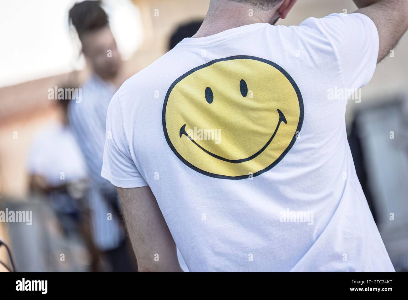 A person seen from the back wearing a shirt with a large, cheerful ...